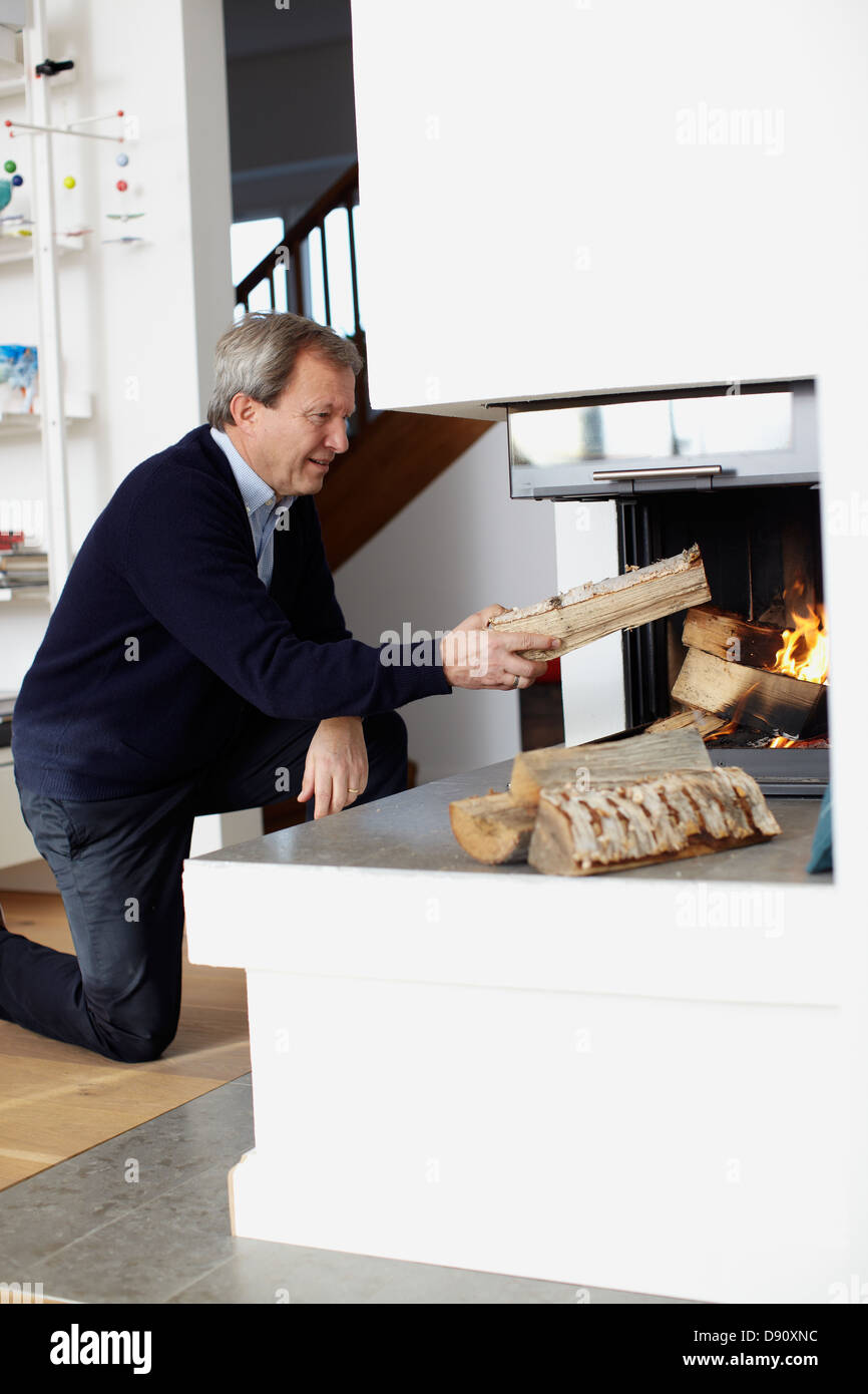 Mature man putting fire wood into fire place Stock Photo - Alamy