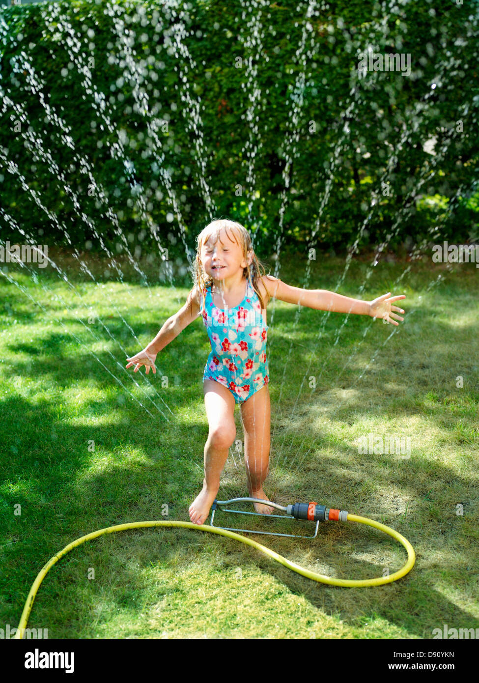 Girl running through sprinkler hi-res stock photography and images - Alamy