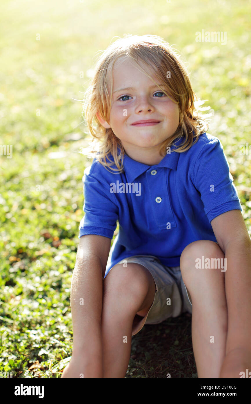 Portrait of boy sitting on grass Stock Photo - Alamy