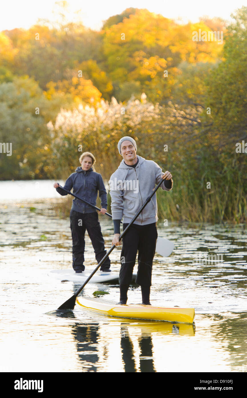 Two people smiling on paddle boards on river Stock Photo - Alamy