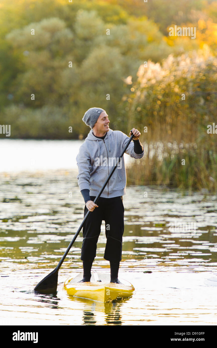 Man rowing paddle board in water Stock Photo - Alamy