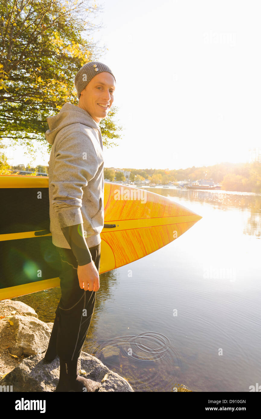 Man carrying paddle board on shore Stock Photo - Alamy