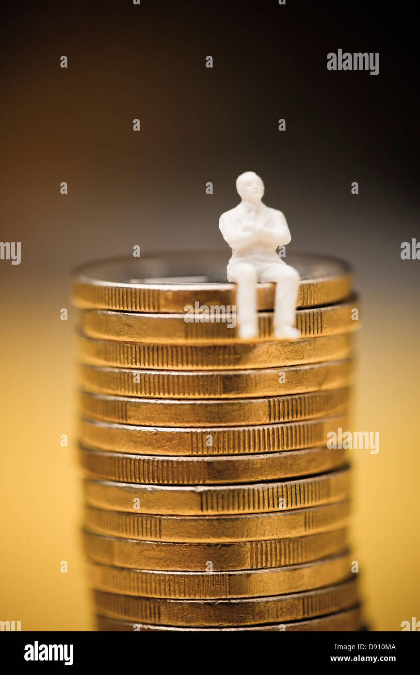 Stack of coins with figurine Stock Photo - Alamy