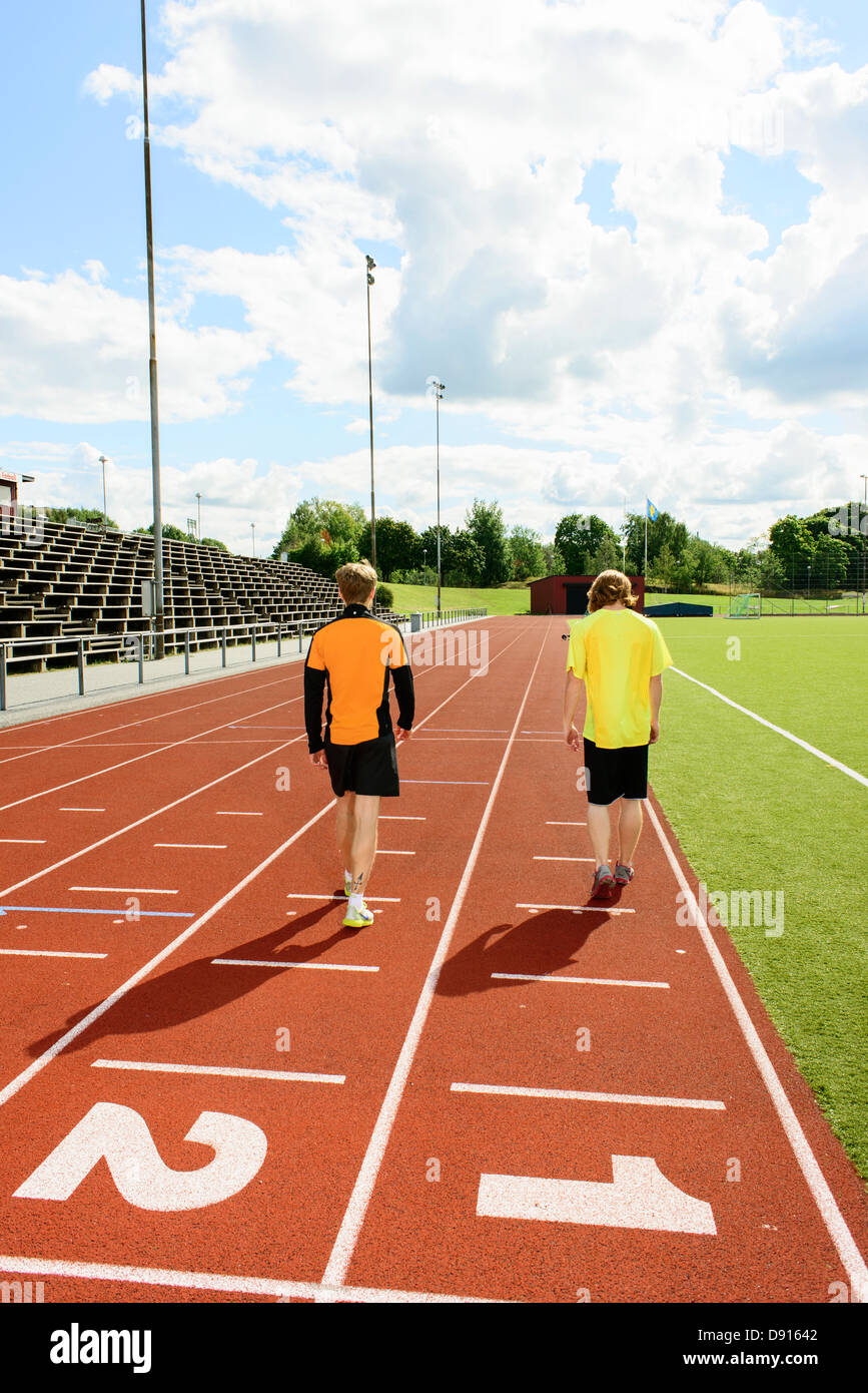 Two men walking down running track Stock Photo - Alamy
