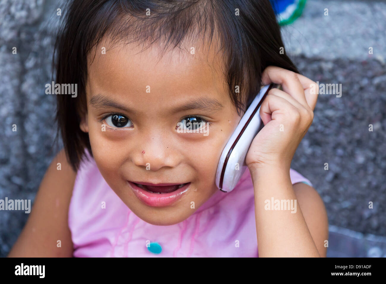Portrait of a Little Girl with mobile Phone in the Street of Manila ...