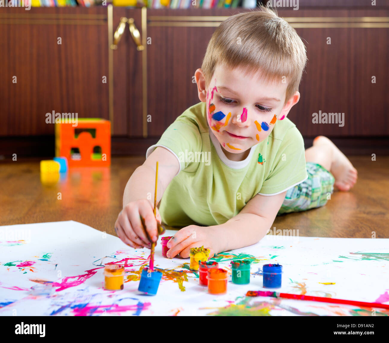 Cute little boy painting on floor at home Stock Photo - Alamy