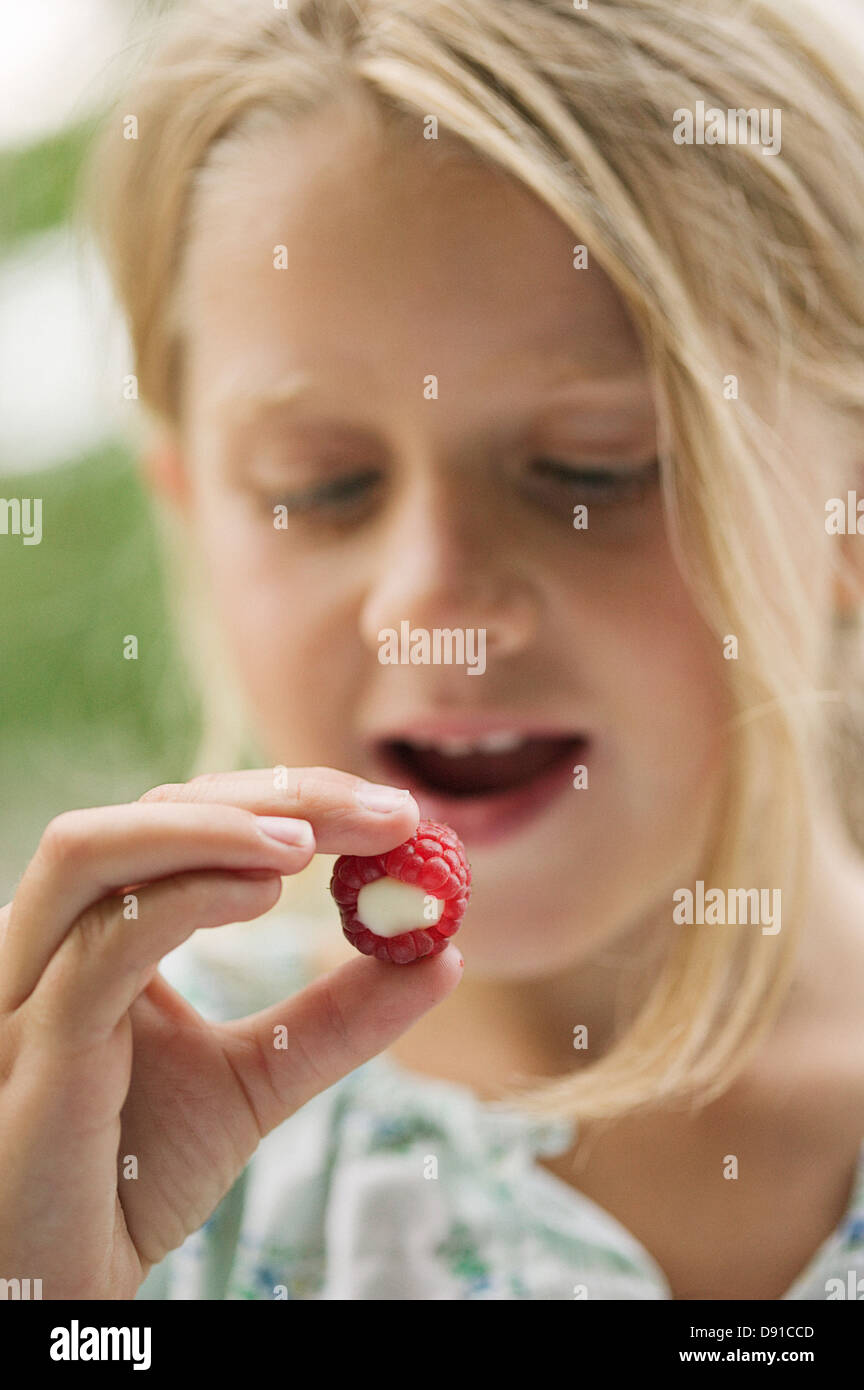 Girl about to eat a raspberry with white chocolate, Sweden Stock Photo ...