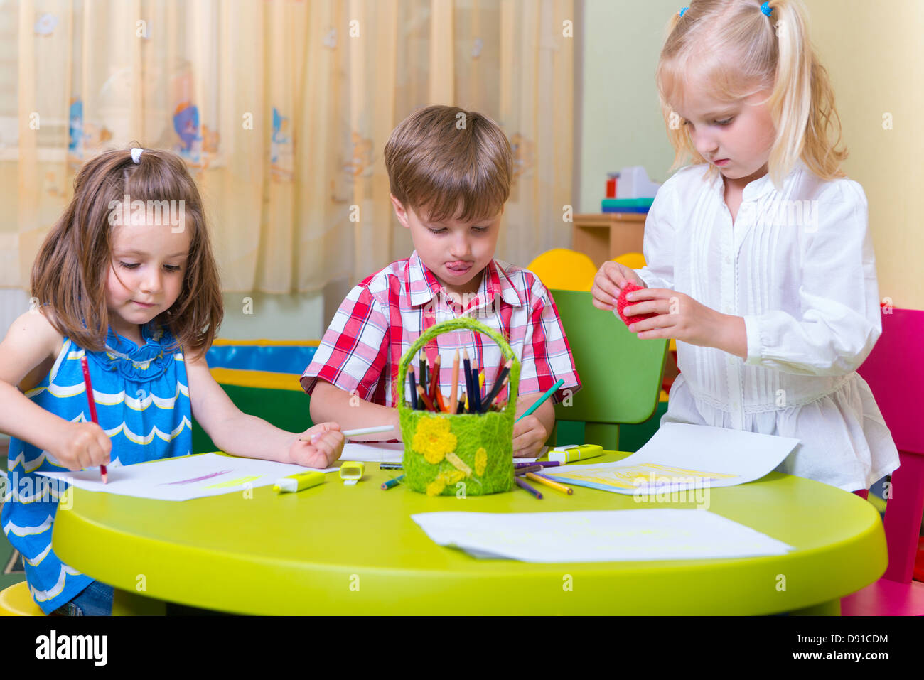 Group of cute little prescool kids drawing with crayons at the table ...