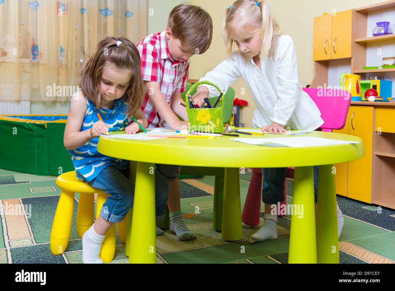 Group of cute little prescool kids drawing with crayons at the table ...