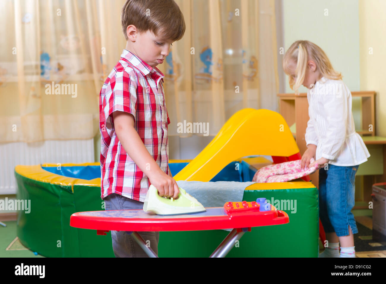 Two cute children playing with iron at home Stock Photo - Alamy