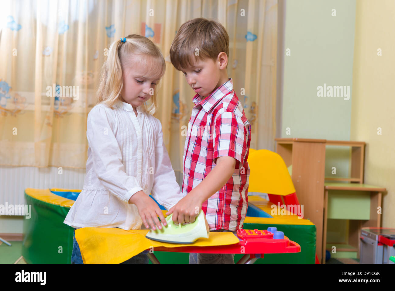 Two cute children playing with iron at home Stock Photo - Alamy