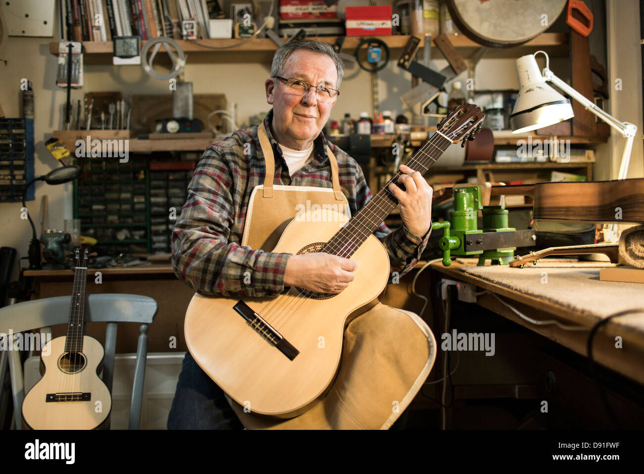 Guitar maker tuning and testing acoustic guitar in workshop, portrait ...