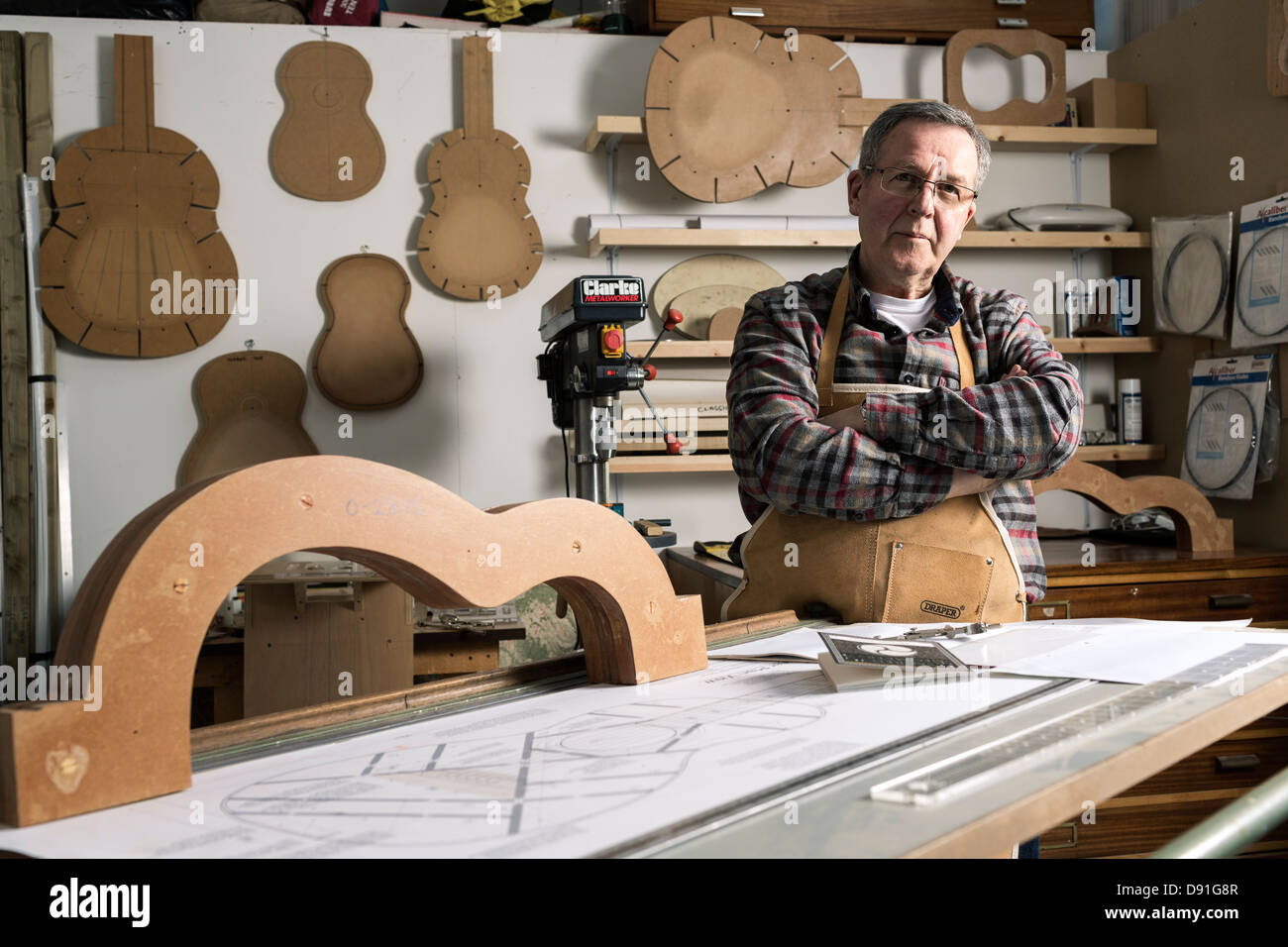 Guitar maker standing by acoustic guitar frame in workshop, portrait ...
