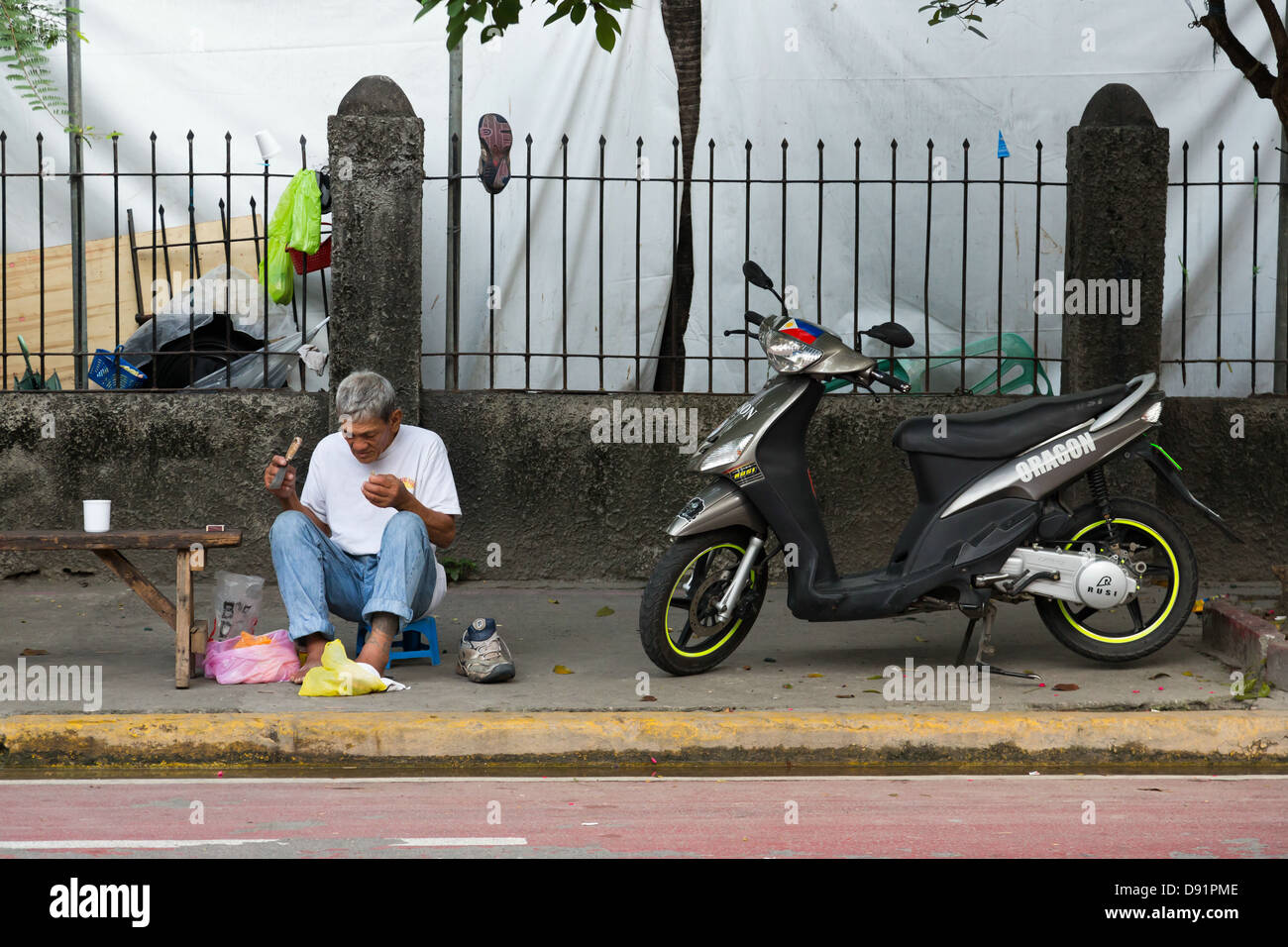 Man sitting on a Sidewalk in Manila, Philippines Stock Photo - Alamy