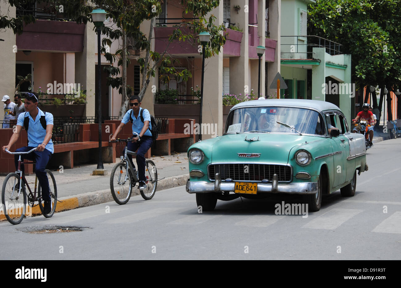 Classic American car passes two cyclists on Cuban street Stock Photo ...