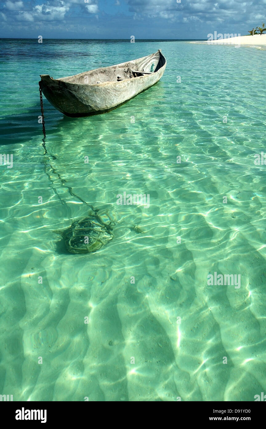 Dugout canoe (pirogue) with stone anchor off a tropical beach, Ile Aux ...