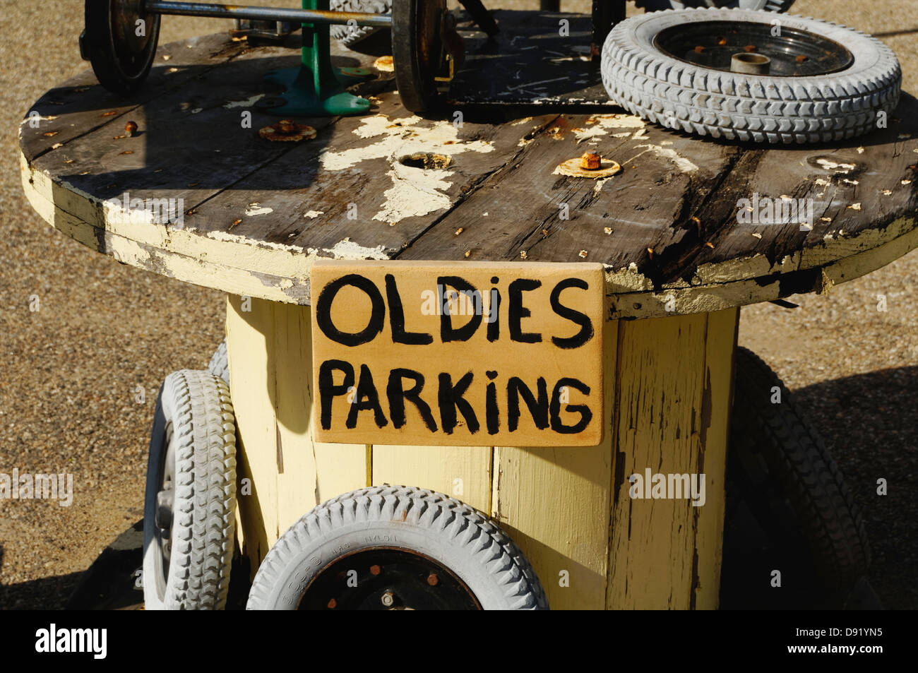 Yellow painted sign reading "Oldies Parking" tacked to a large cable ...