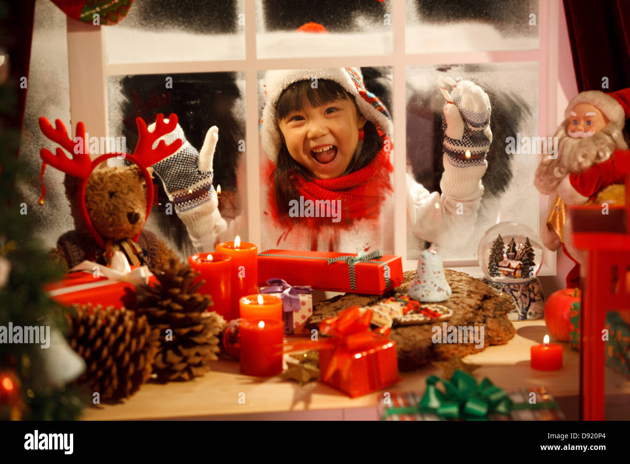 Girl looking at Christmas gift through window Stock Photo - Alamy