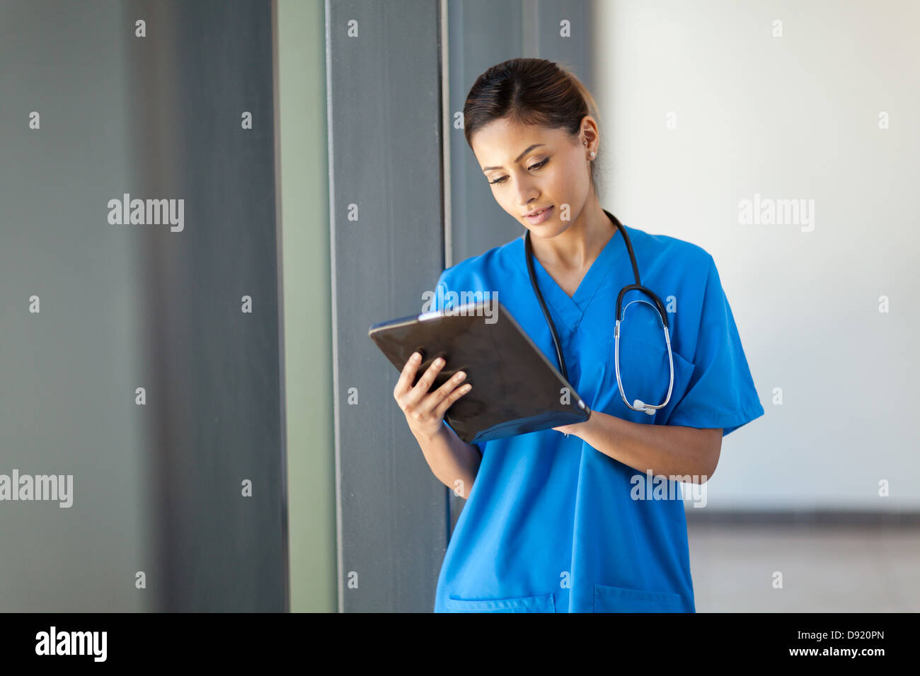 young female medical nurse using tablet computer in hospital office ...