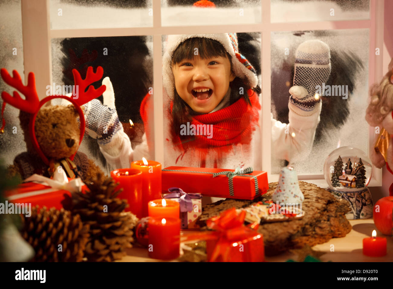 Girl looking at Christmas gift through window Stock Photo - Alamy