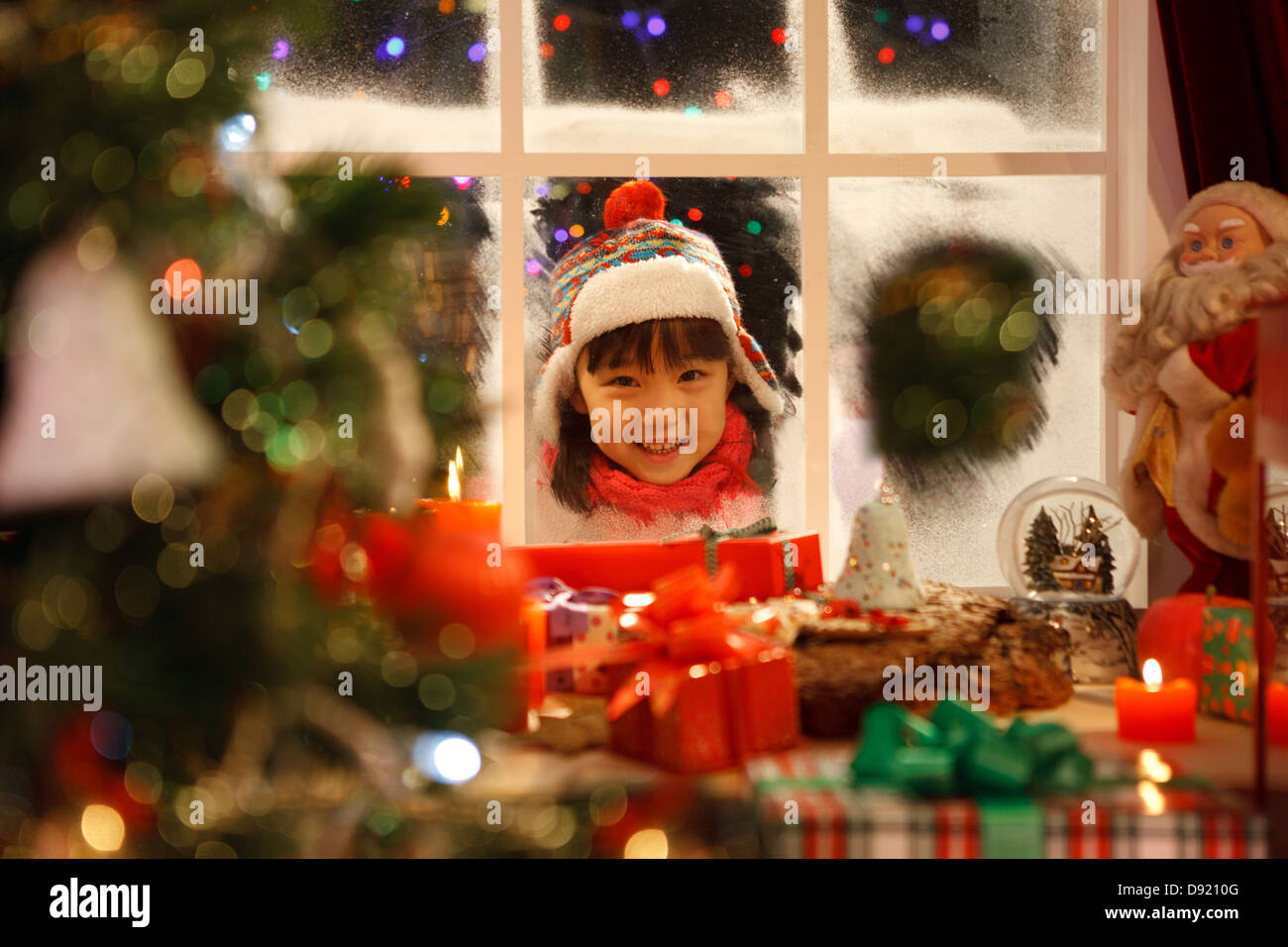 Girl looking at Christmas gift through window Stock Photo - Alamy