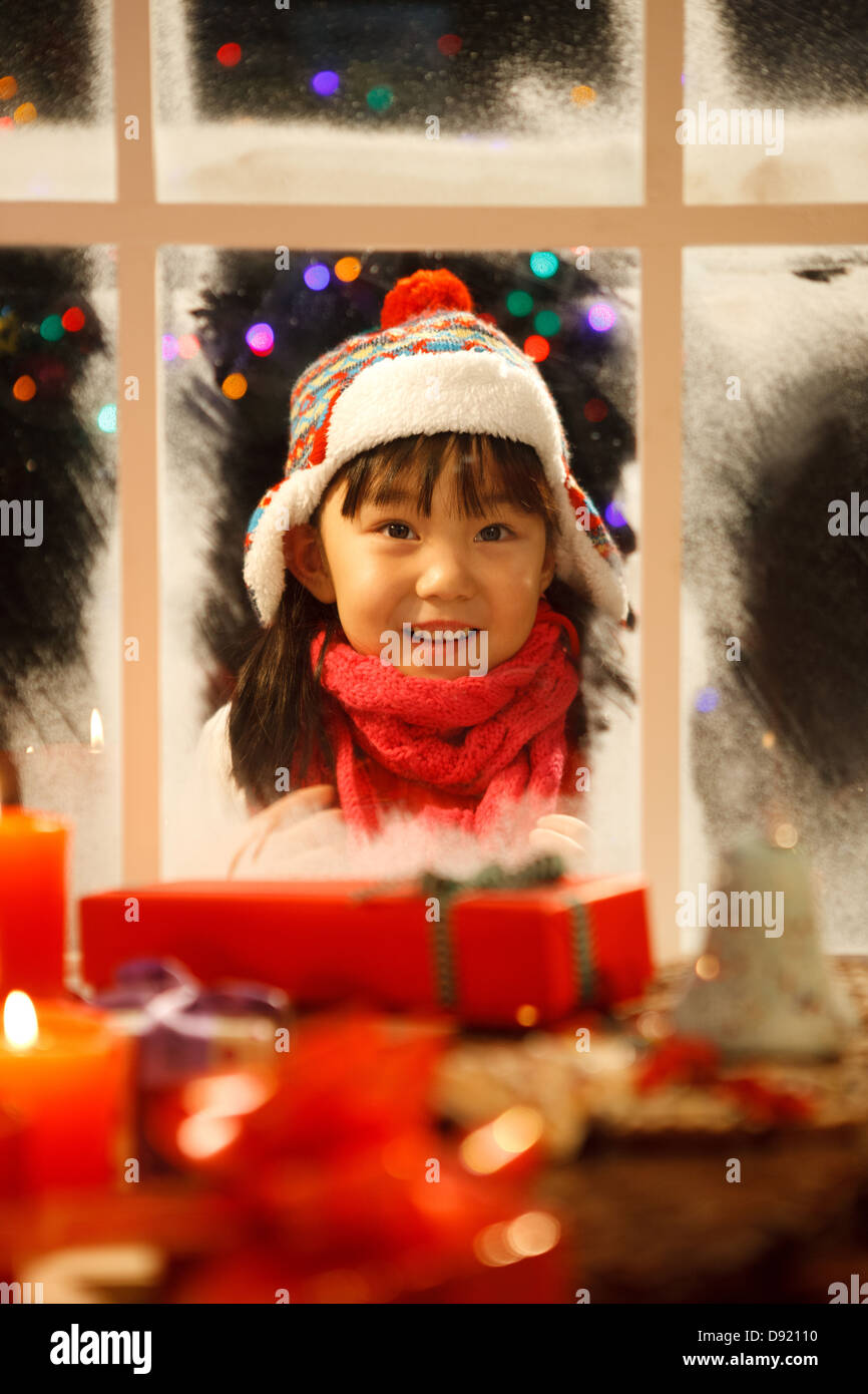 Girl looking at Christmas gift through window Stock Photo - Alamy