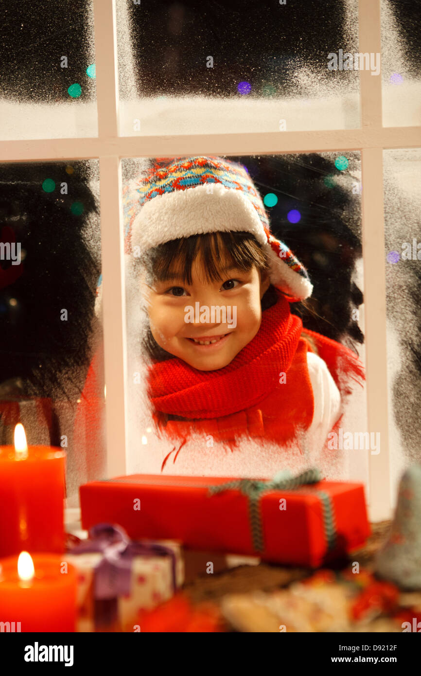 Girl looking at Christmas gift through window Stock Photo - Alamy