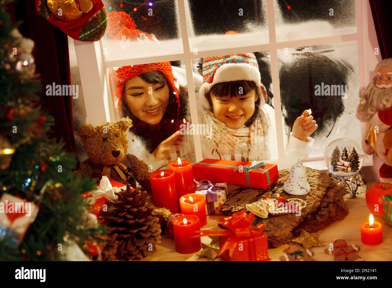 Young woman and girl looking at Christmas gift through window Stock ...