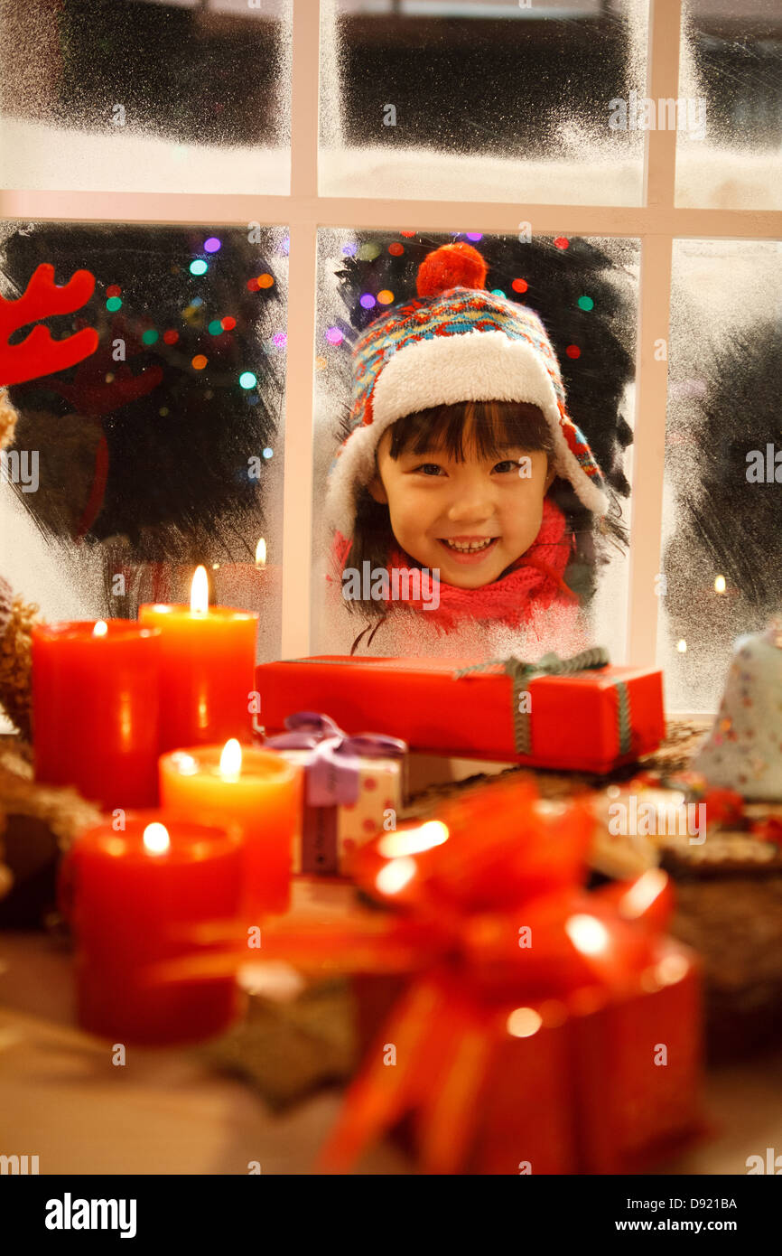 Girl looking at Christmas gift through window Stock Photo - Alamy