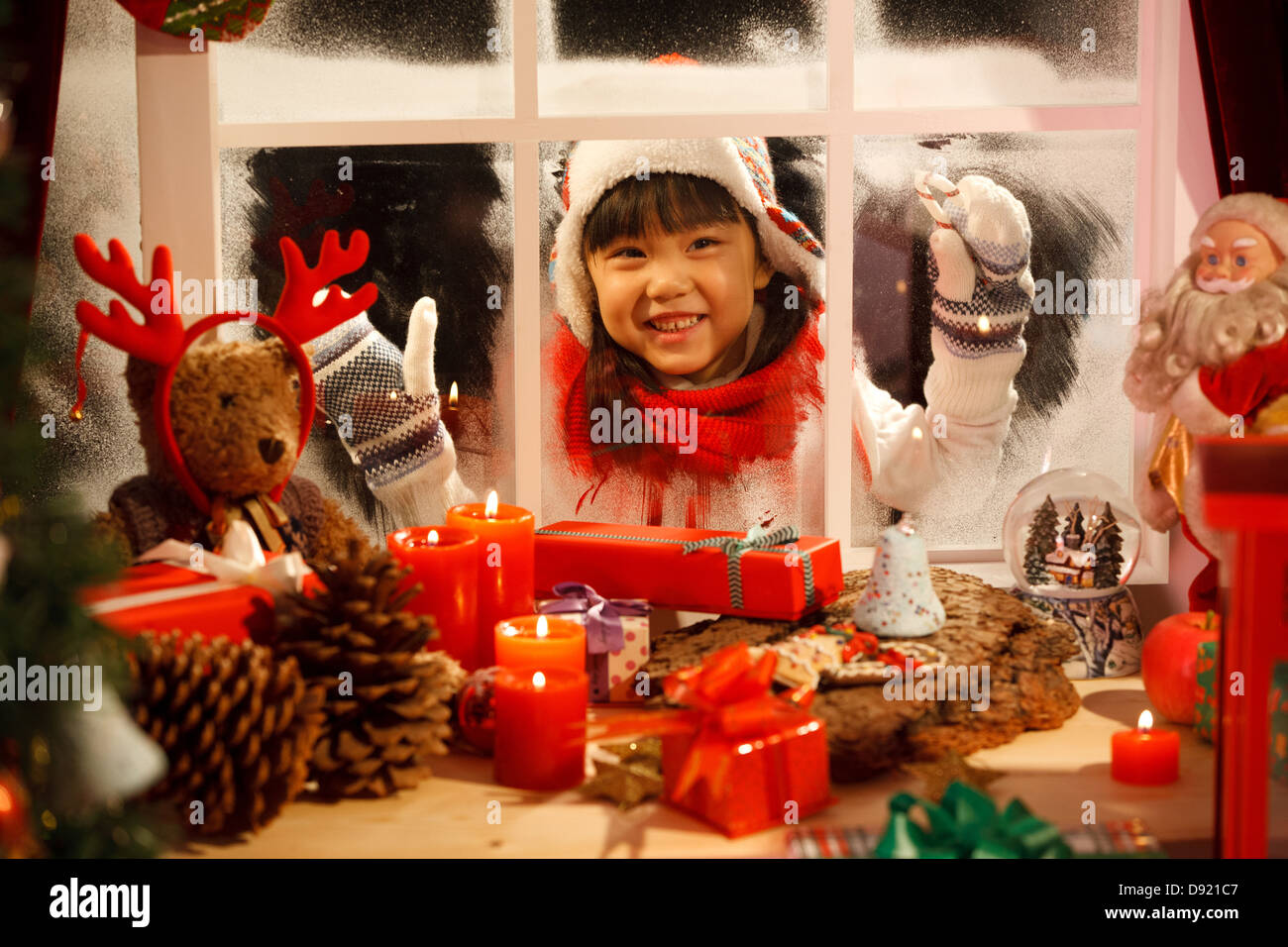 Girl looking at Christmas gift through window Stock Photo - Alamy