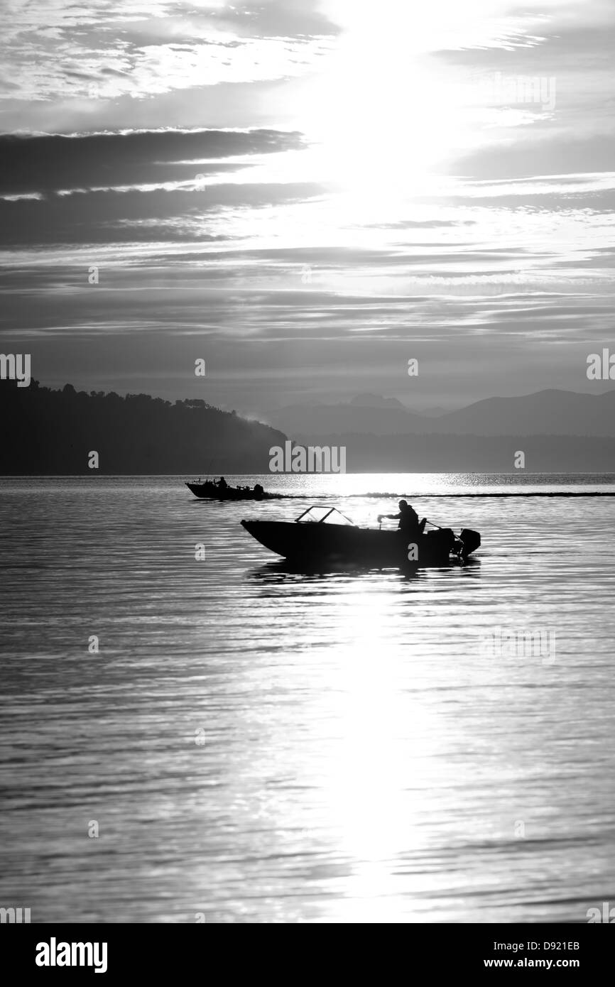 Boats troll for Salmon awash in bright light at sunset Stock Photo - Alamy