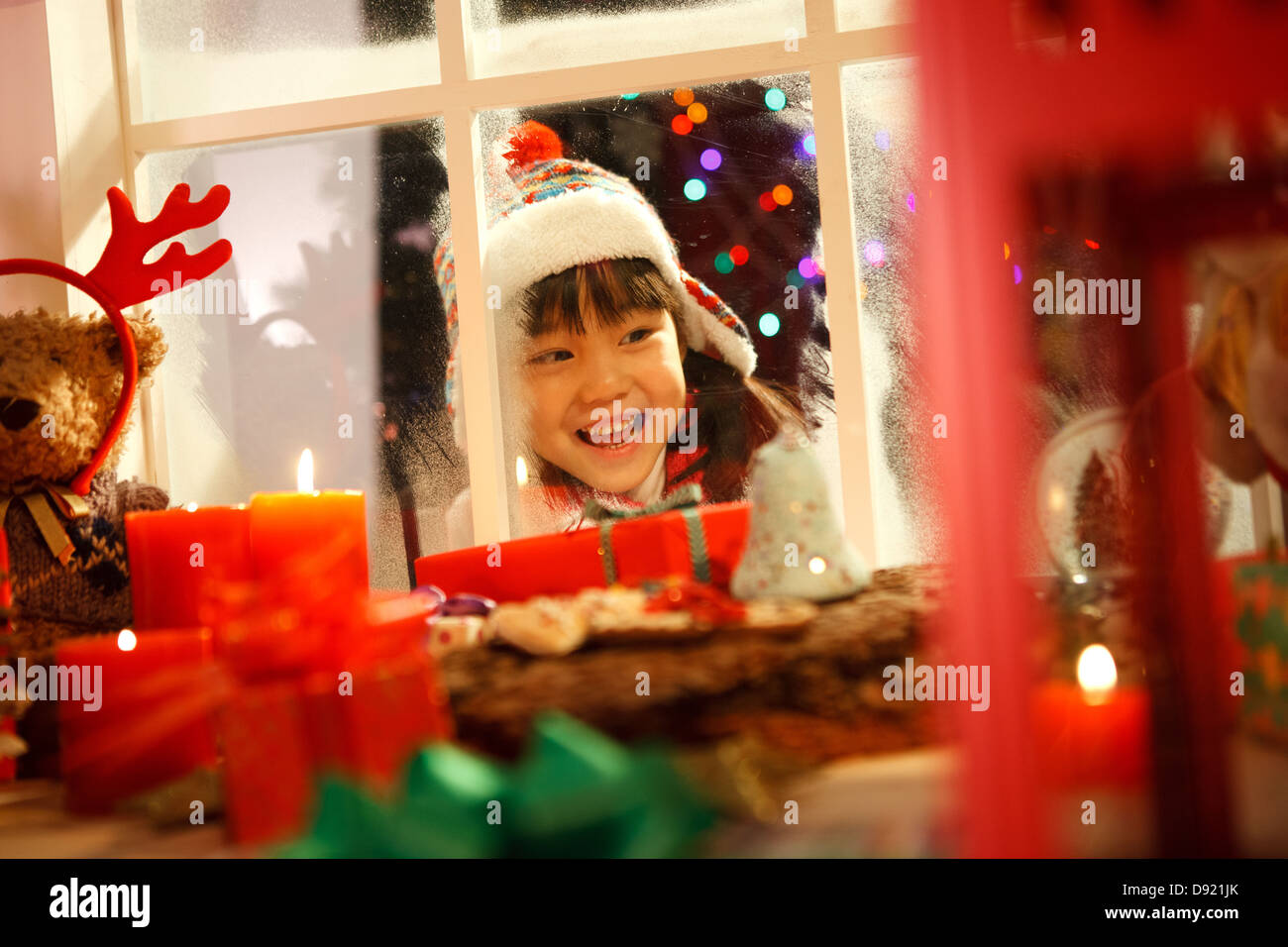 Girl looking at Christmas gift through window Stock Photo - Alamy