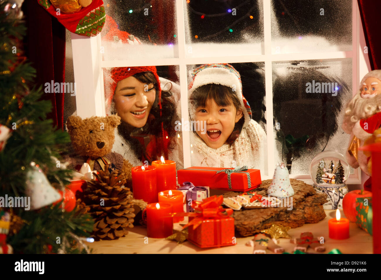Young woman and girl looking at Christmas gift through window Stock ...