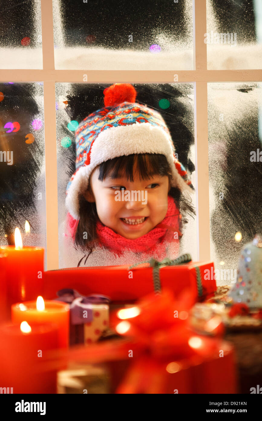 Girl looking at Christmas gift through window Stock Photo - Alamy