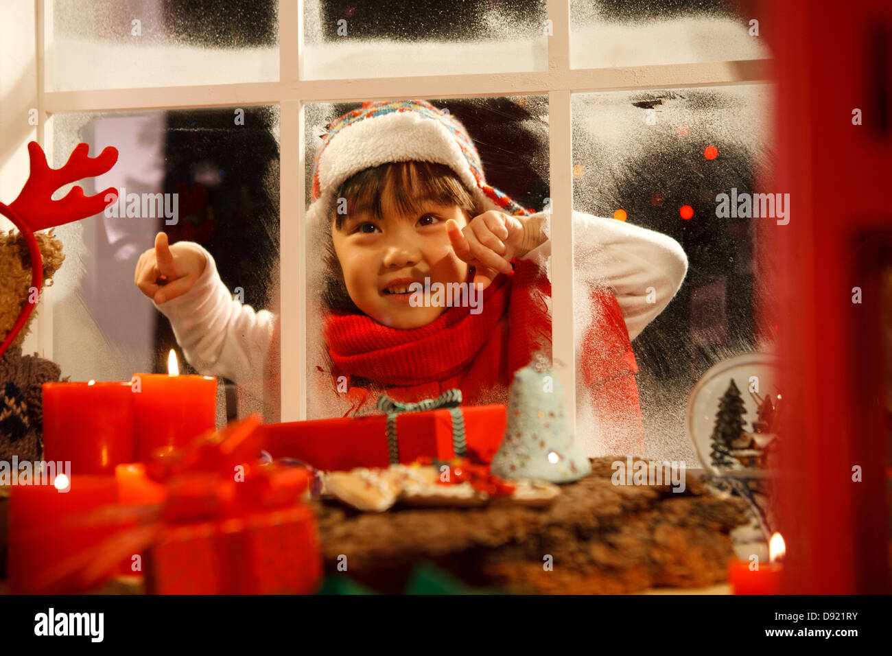 Girl looking at Christmas gift through window Stock Photo - Alamy