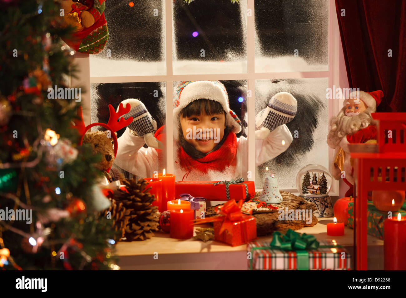 Girl looking at Christmas gift through window Stock Photo - Alamy