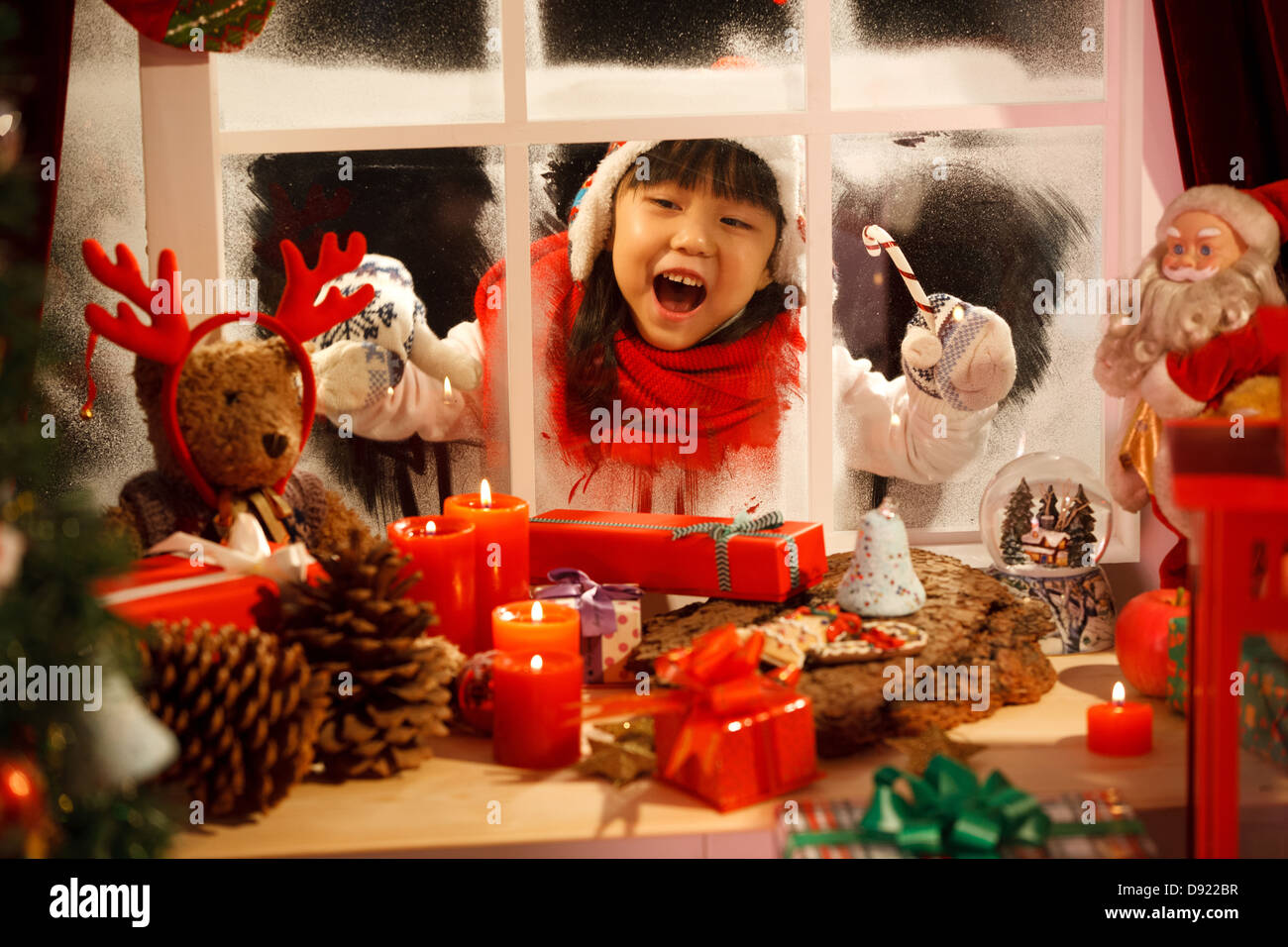Girl looking at Christmas gift through window Stock Photo - Alamy