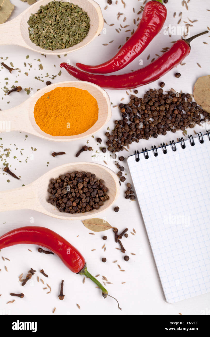notebook, red chilli pepper, spices in spoons on a white background ...