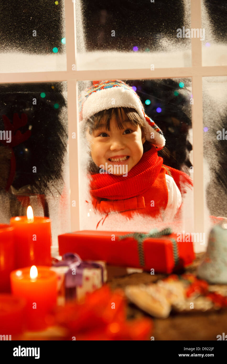 Girl looking at Christmas gift through window Stock Photo - Alamy