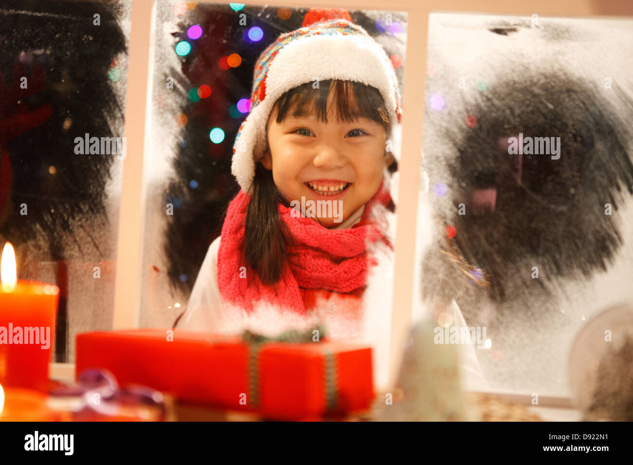 Girl looking at Christmas gift through window Stock Photo - Alamy
