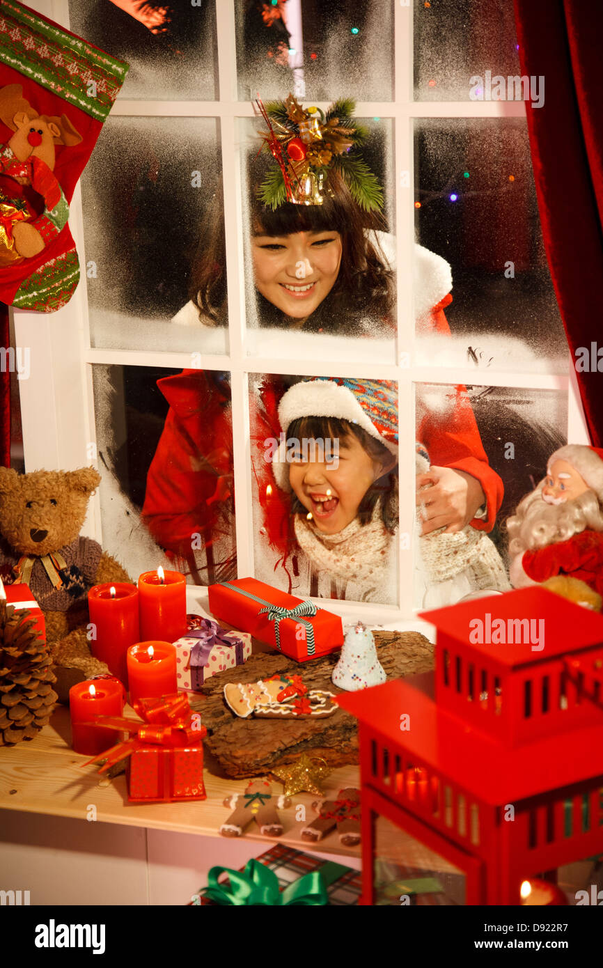 Young woman and girl looking at Christmas gift through window Stock ...