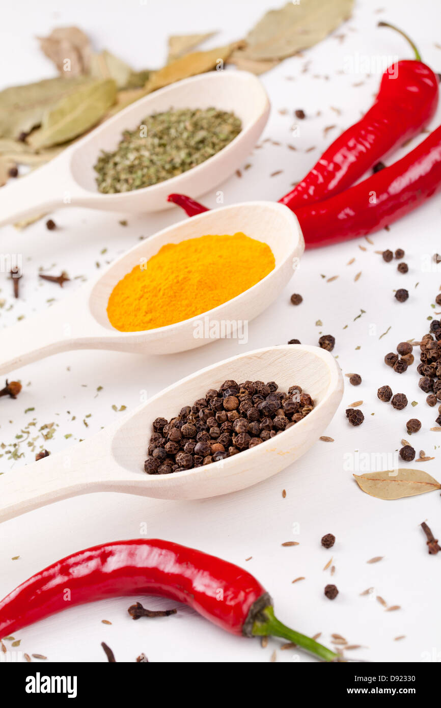 red hot peppers and other kind of spices in spoons on a white ...