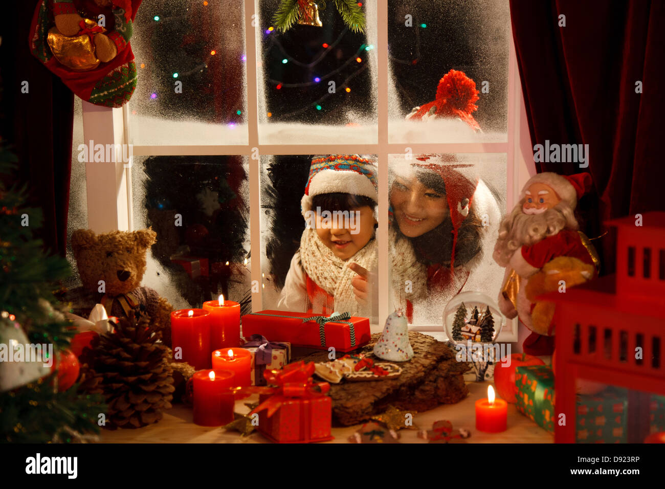 Girl and young woman looking at Christmas gifts through window Stock ...
