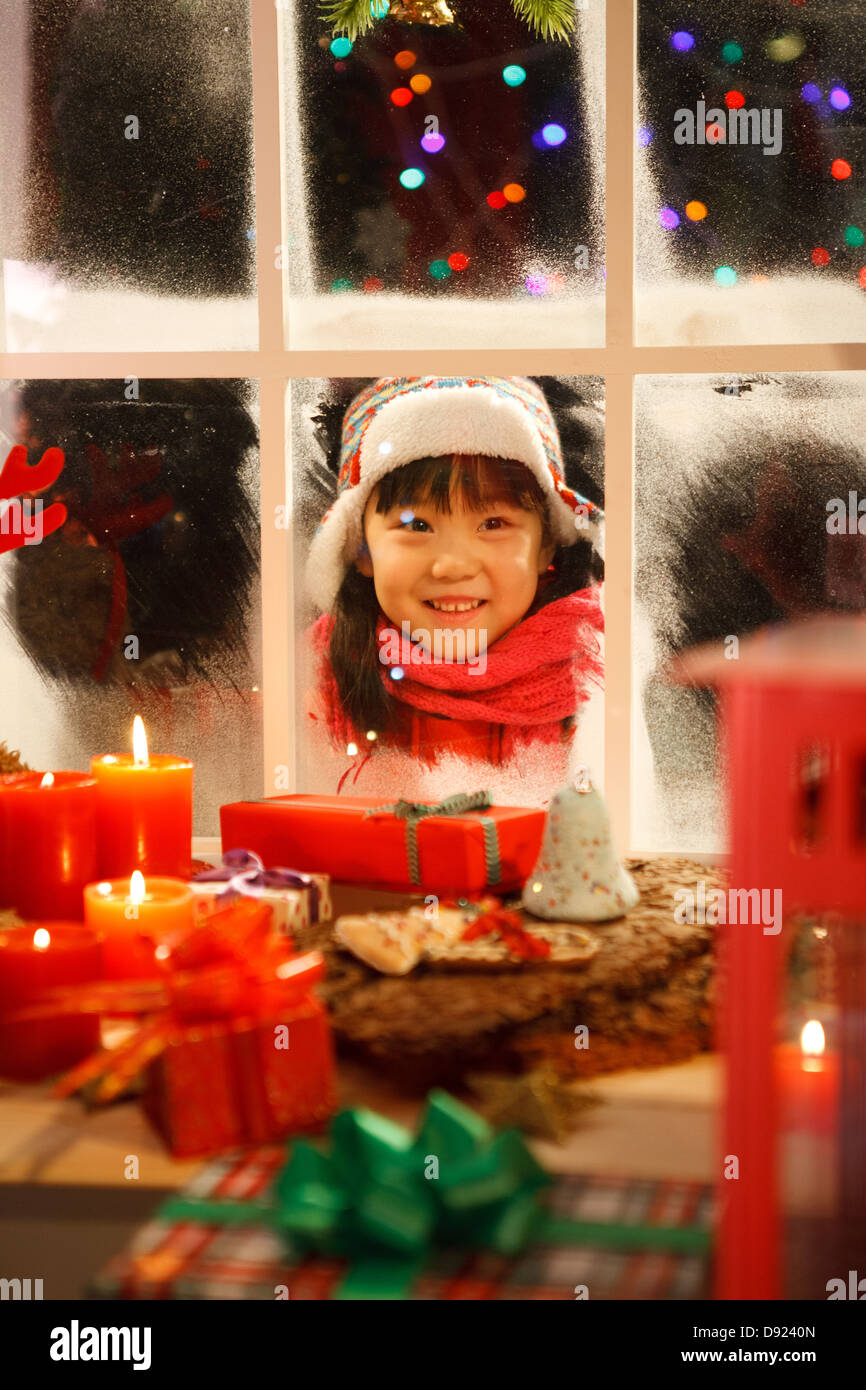 Girl looking at Christmas gift through window Stock Photo - Alamy