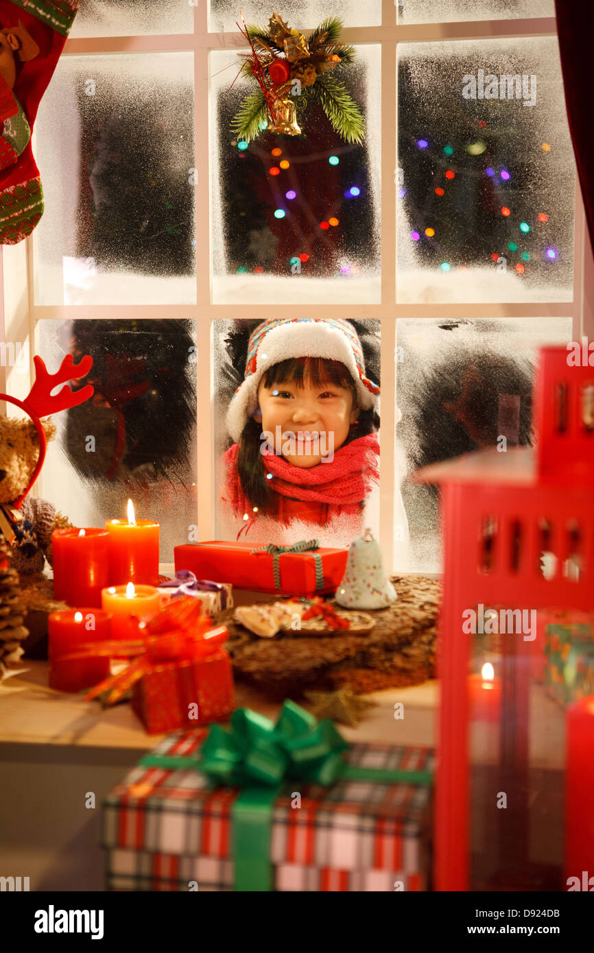 Girl looking at Christmas gift through window Stock Photo - Alamy