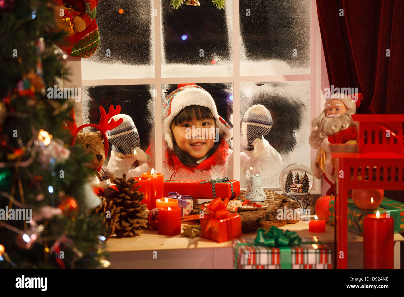 Girl looking at Christmas gift through window Stock Photo - Alamy