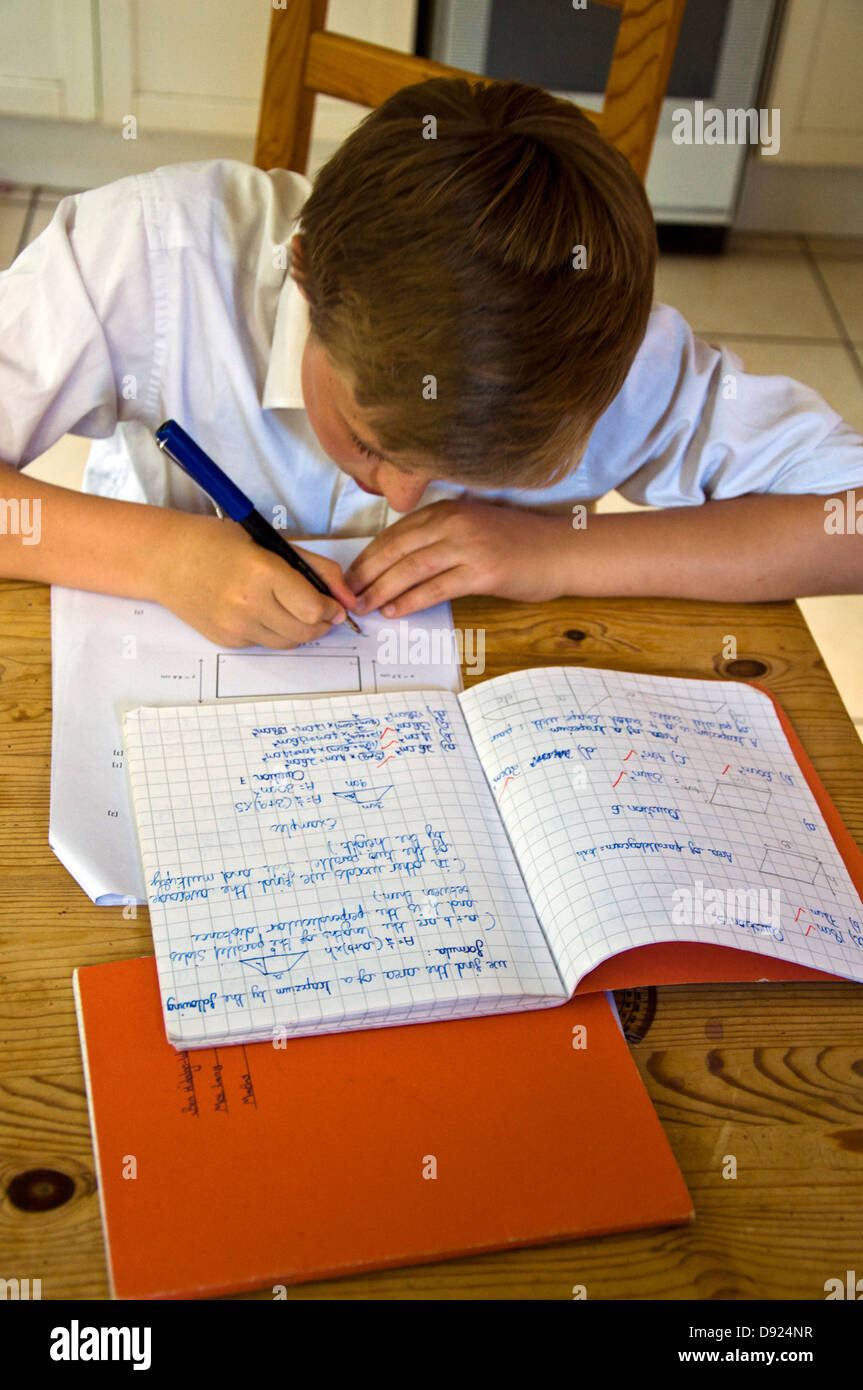 Thirteen 13 year old boy doing mathematics homework on kitchen table ...
