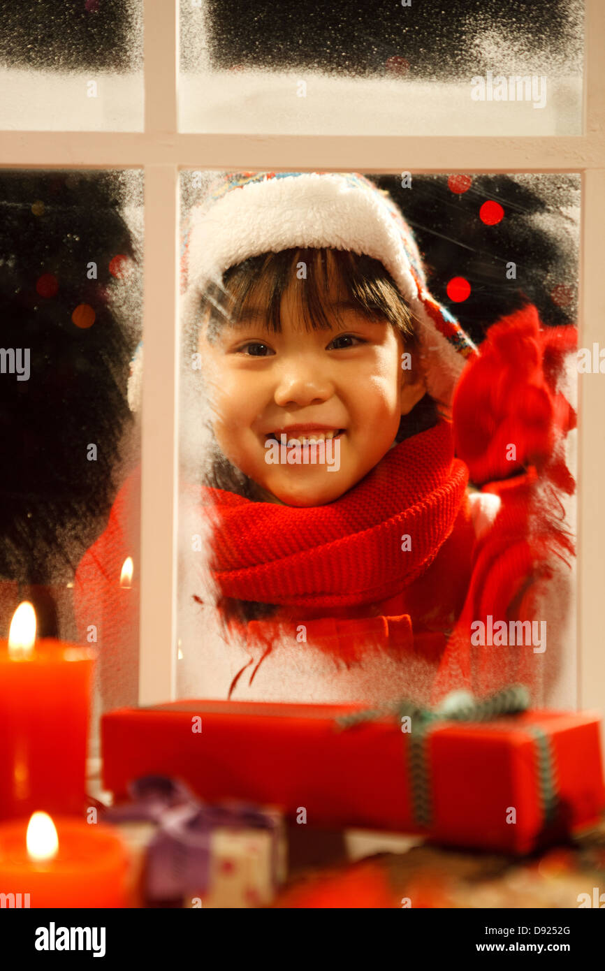 Girl looking at Christmas gift through window Stock Photo - Alamy