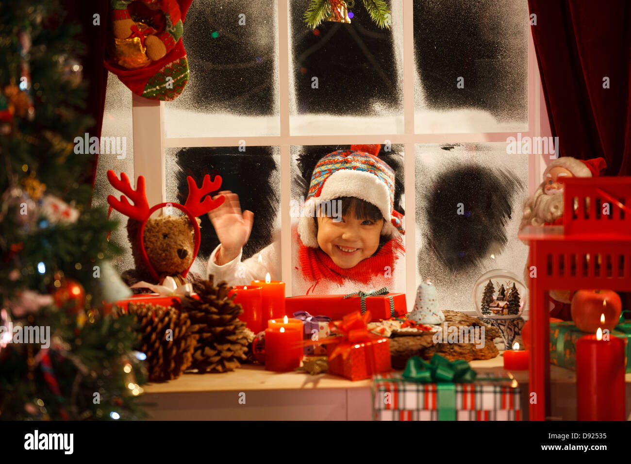 Girl looking at Christmas gift through window Stock Photo - Alamy