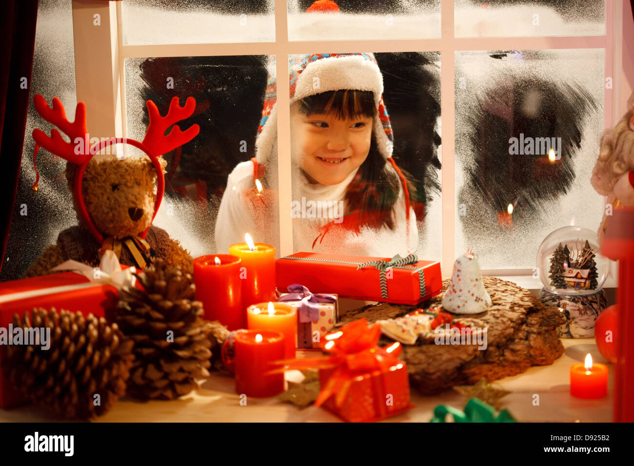 Girl looking at Christmas gift through window Stock Photo - Alamy